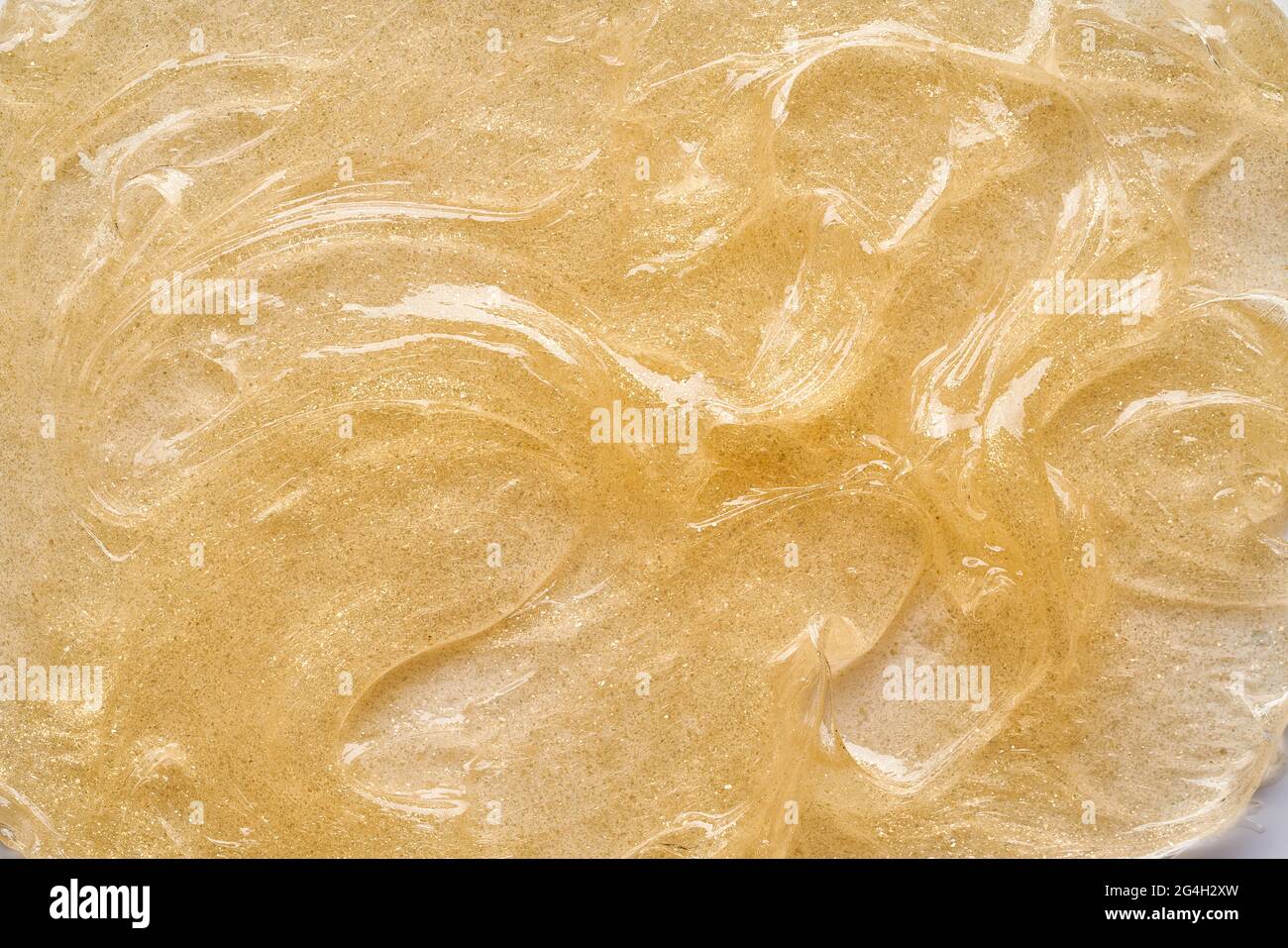 Transparent smear and texture of golden cosmetic gel on a white ...