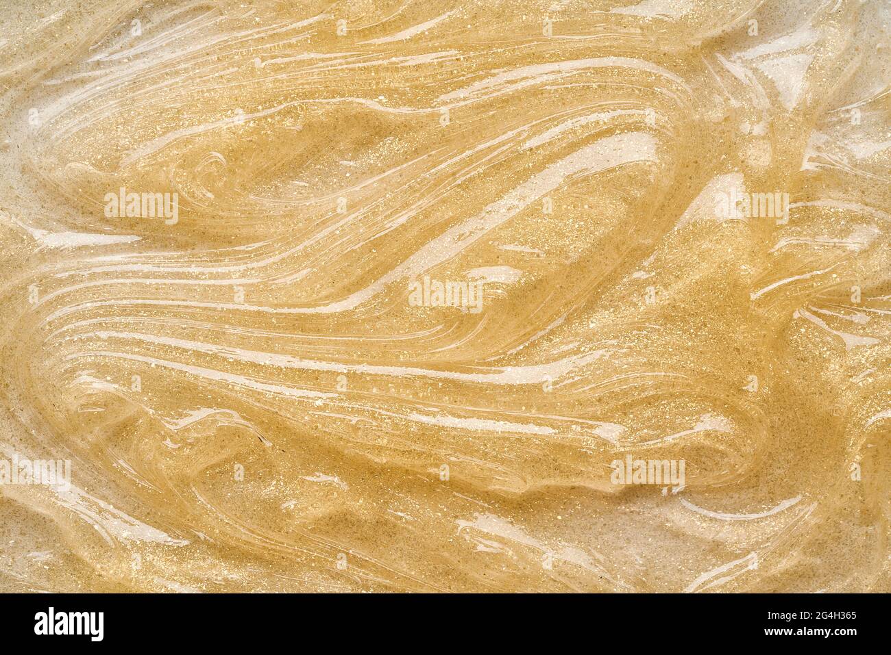 Transparent smear and texture of golden cosmetic gel on a white ...