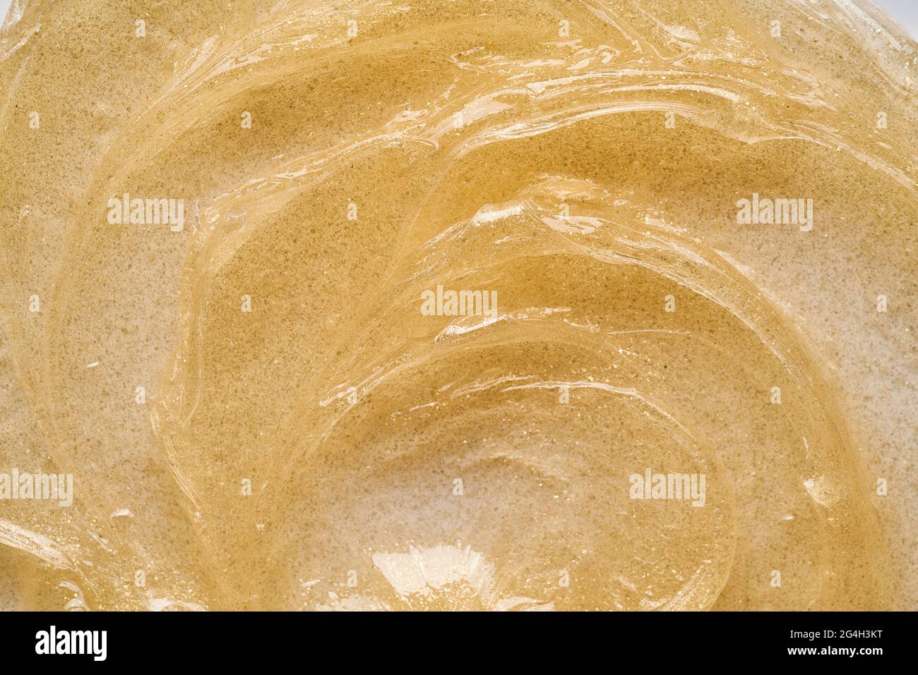 Transparent smear and texture of golden cosmetic gel on a white ...
