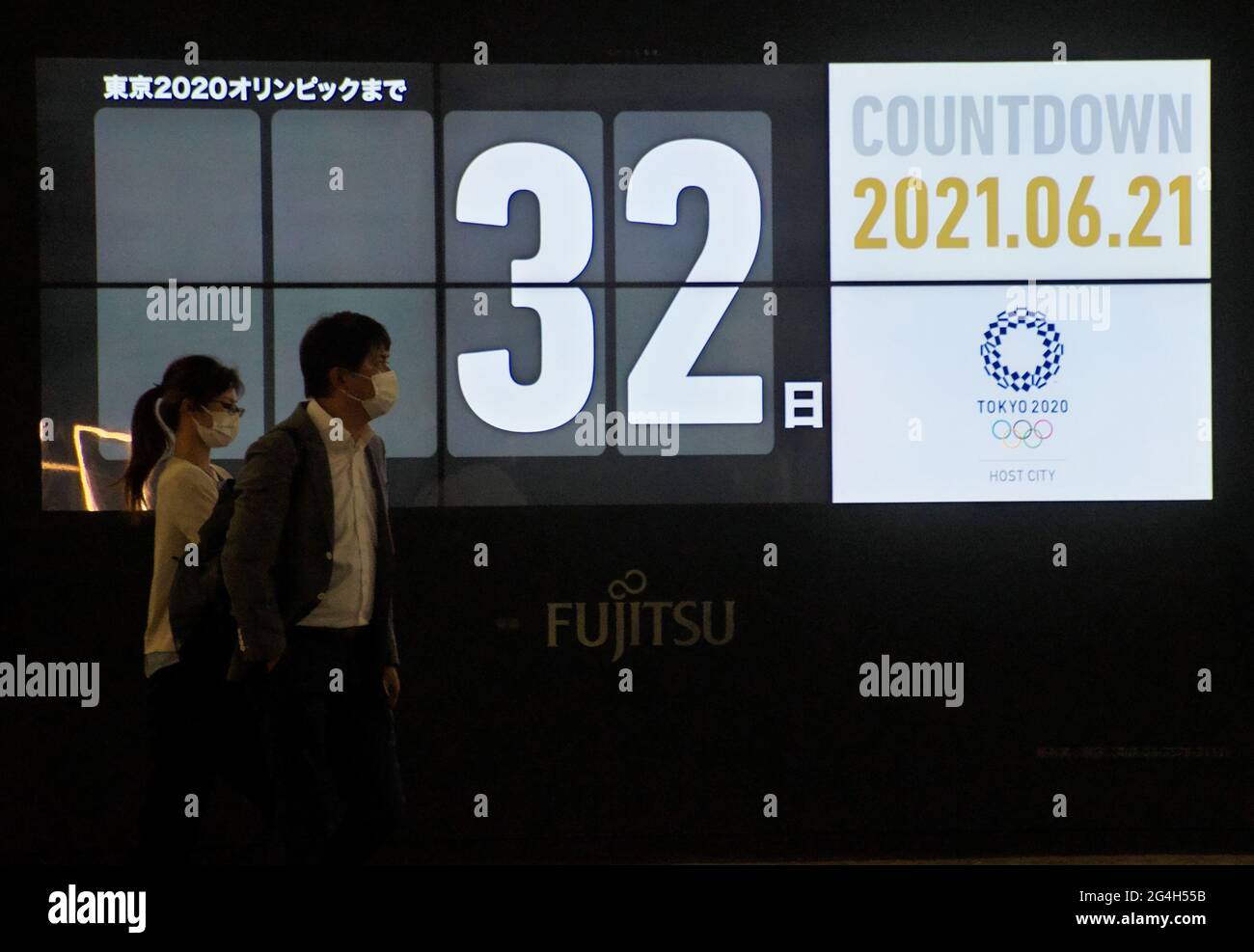 Tokyo, Japan. 21st June, 2021. Pedestrians walk past the countdown ...