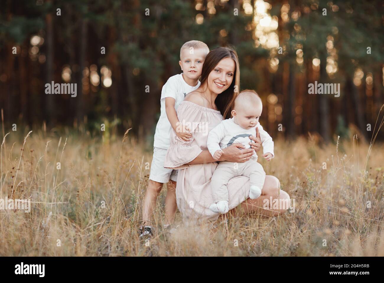 Young mother hugging her two little sons. Family holiday in the park ...
