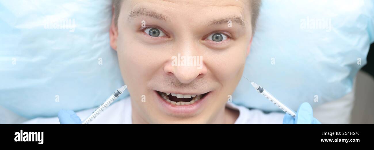 Portrait of frightened man who is being given several injections at ...