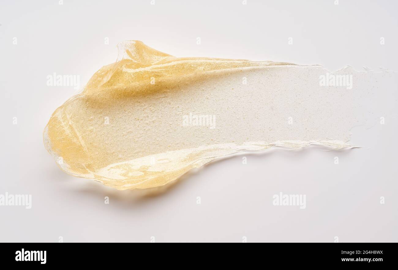 Transparent smear and texture of golden cosmetic gel on a white ...
