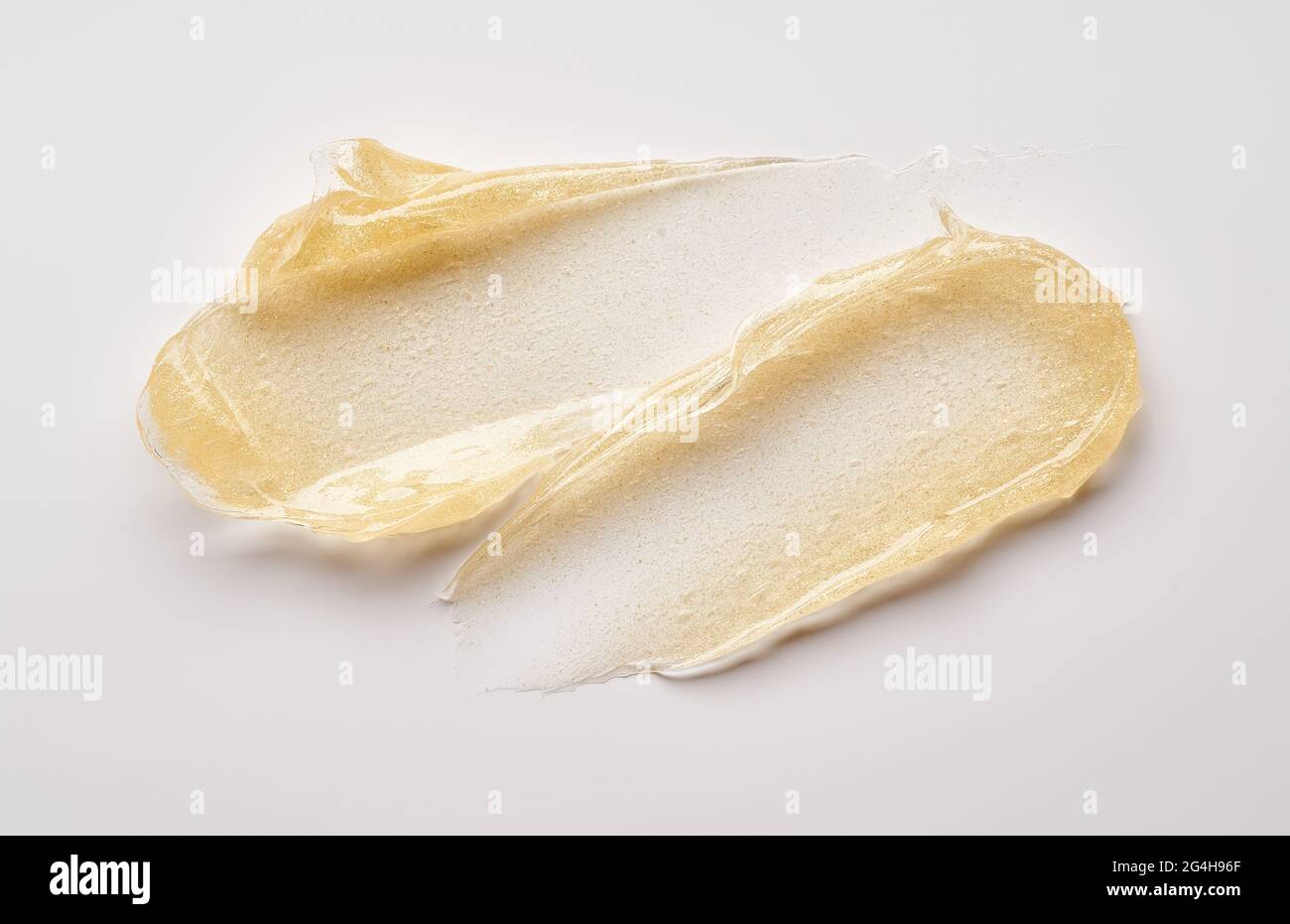 Transparent smear and texture of golden cosmetic gel on a white ...