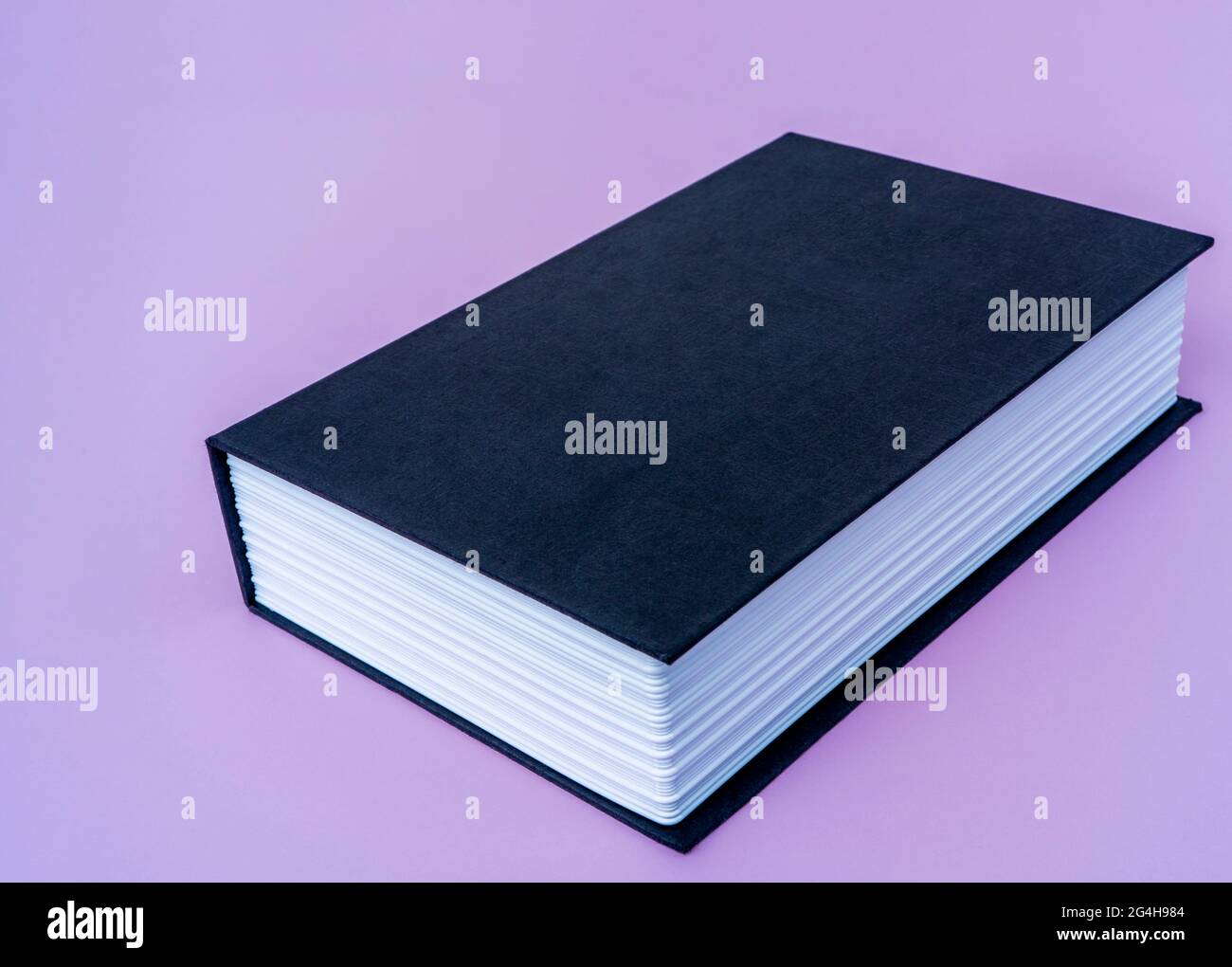 Big black book on violet isolated background with copy space for your ...