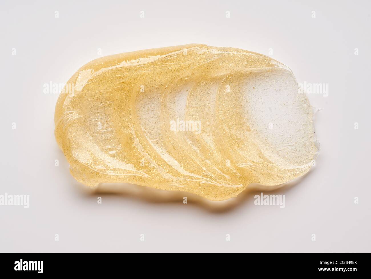 Transparent smear and texture of golden cosmetic gel on a white ...
