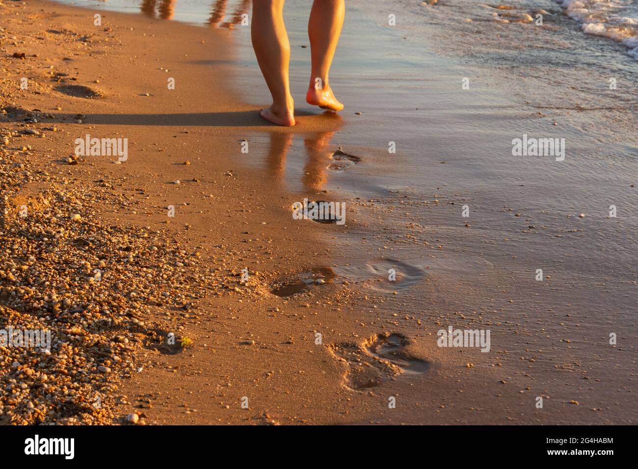People beach feet close-up. Small waves roll up on the shore and the ...
