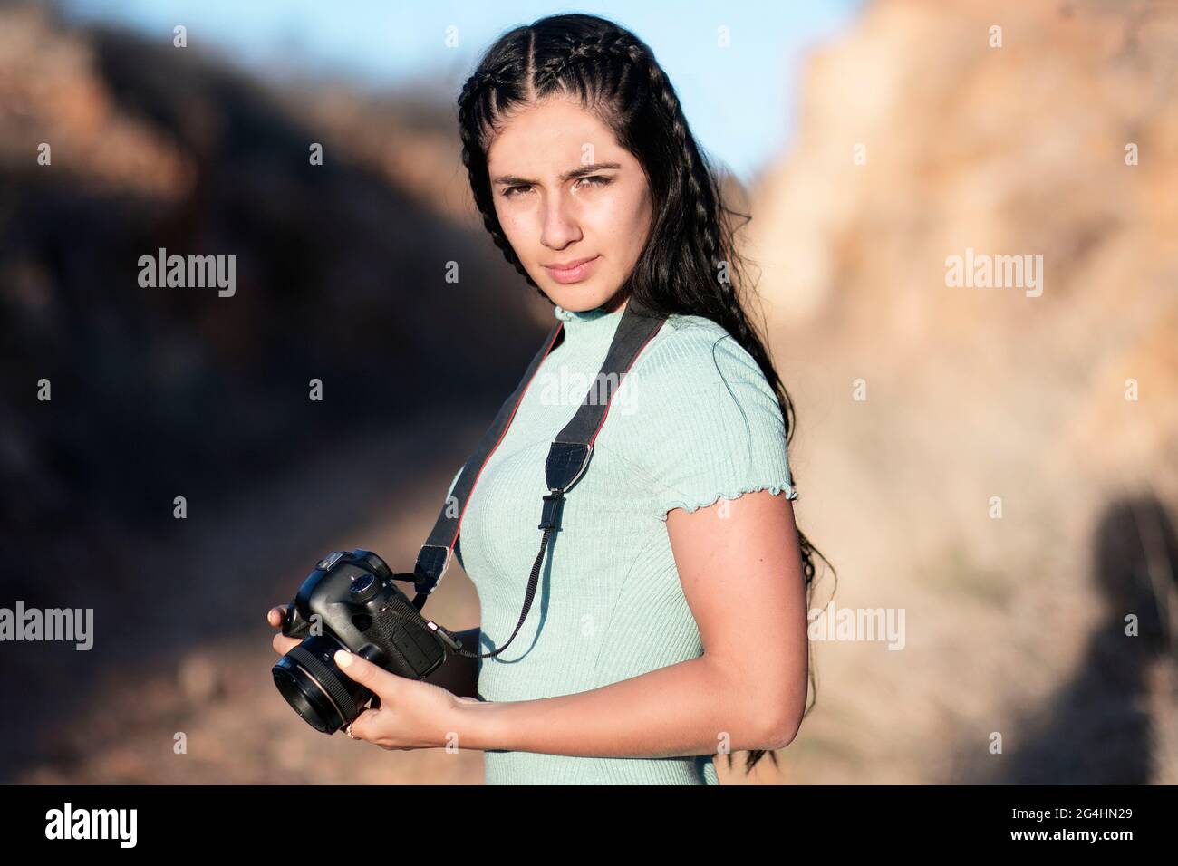 young woman photographer with reflex camera in hands looking straight ...