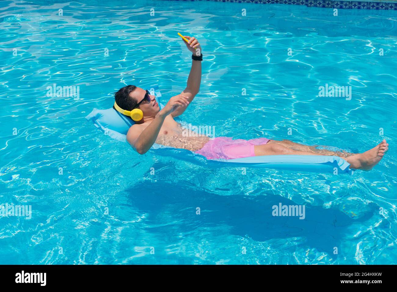 Young Latino man at the pool using his cell phone Stock Photo - Alamy