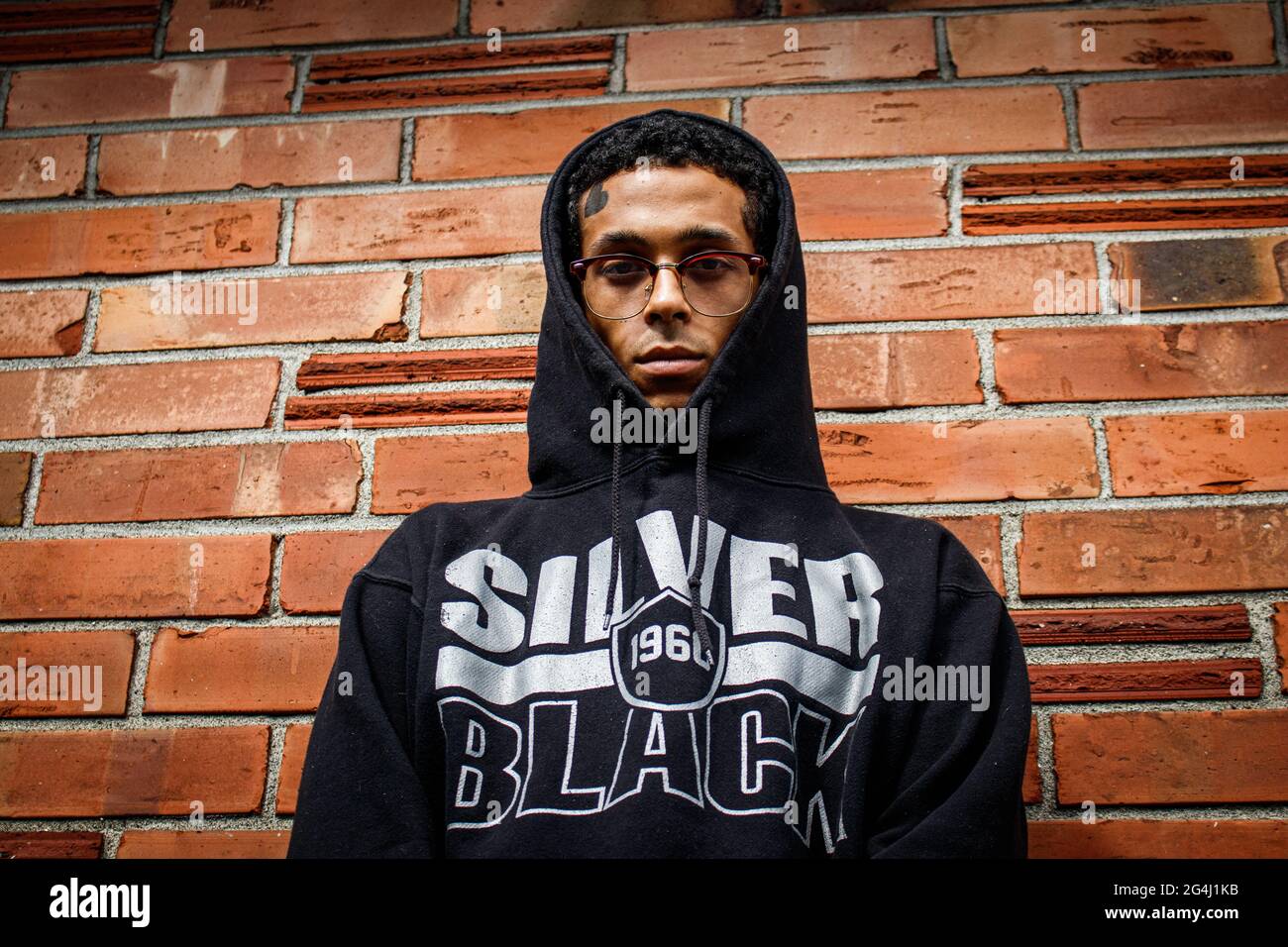 Titled: Power - Boy standing in front of brick wall, wearing an orange ...