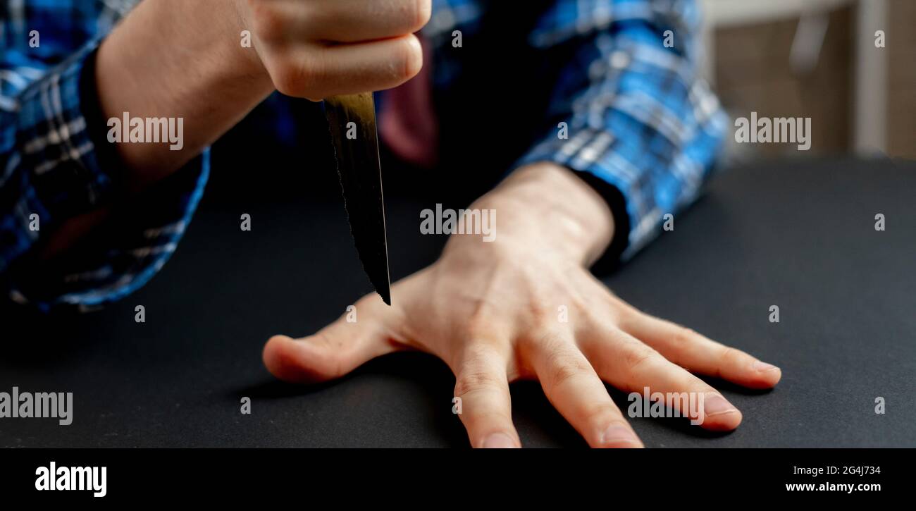 a hand with knife hitting between the fingers on the table, playing the ...