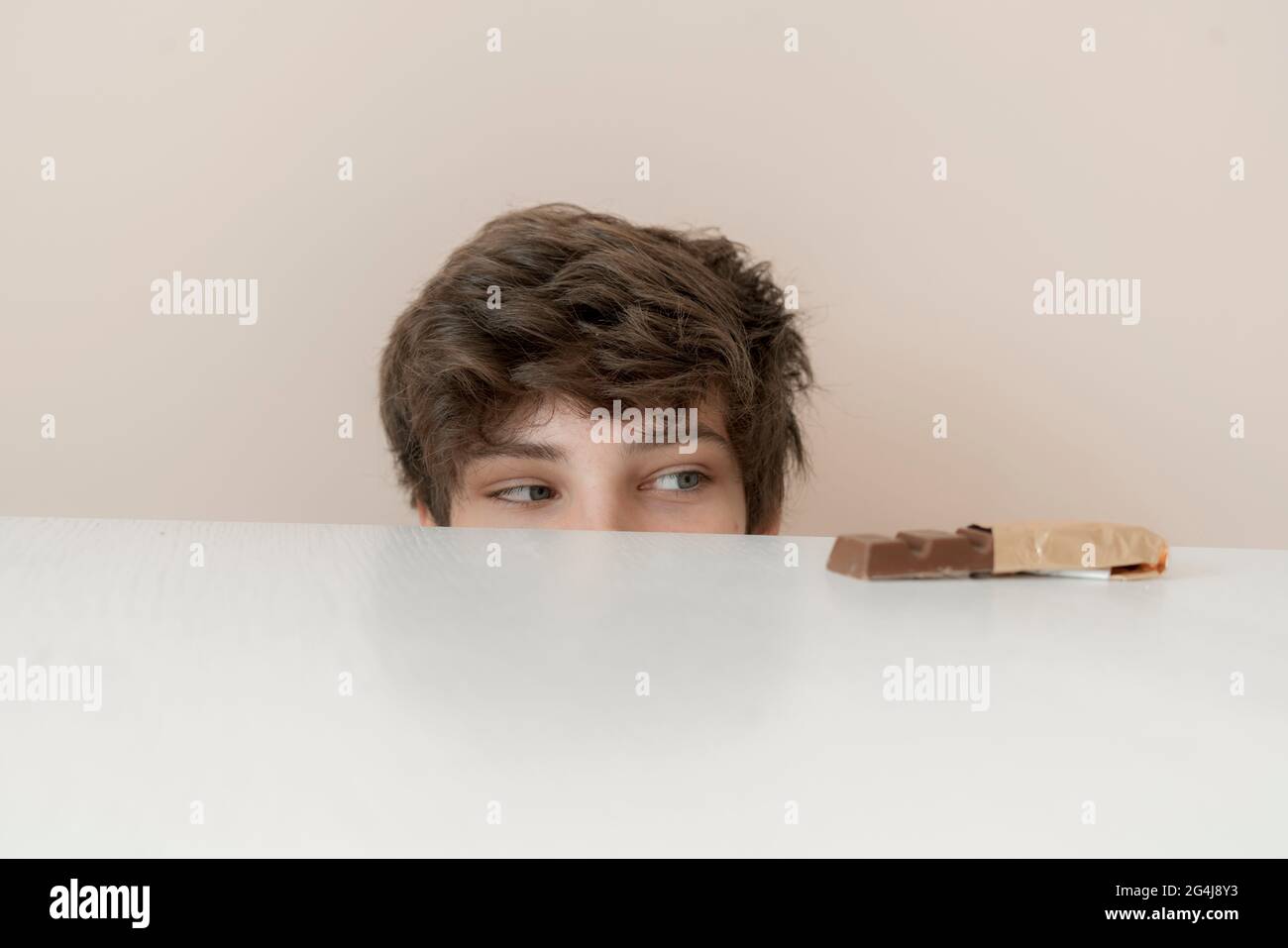 male teenager face eyes above the table picking snatching the sweet ...