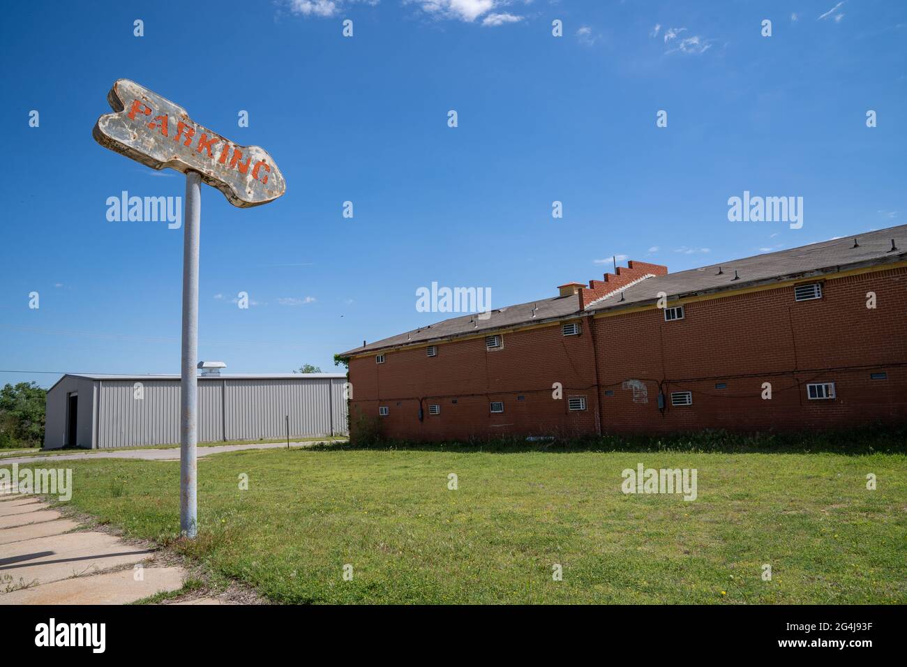 Old rusty generic parking sign with an arrow points to a grassy field ...