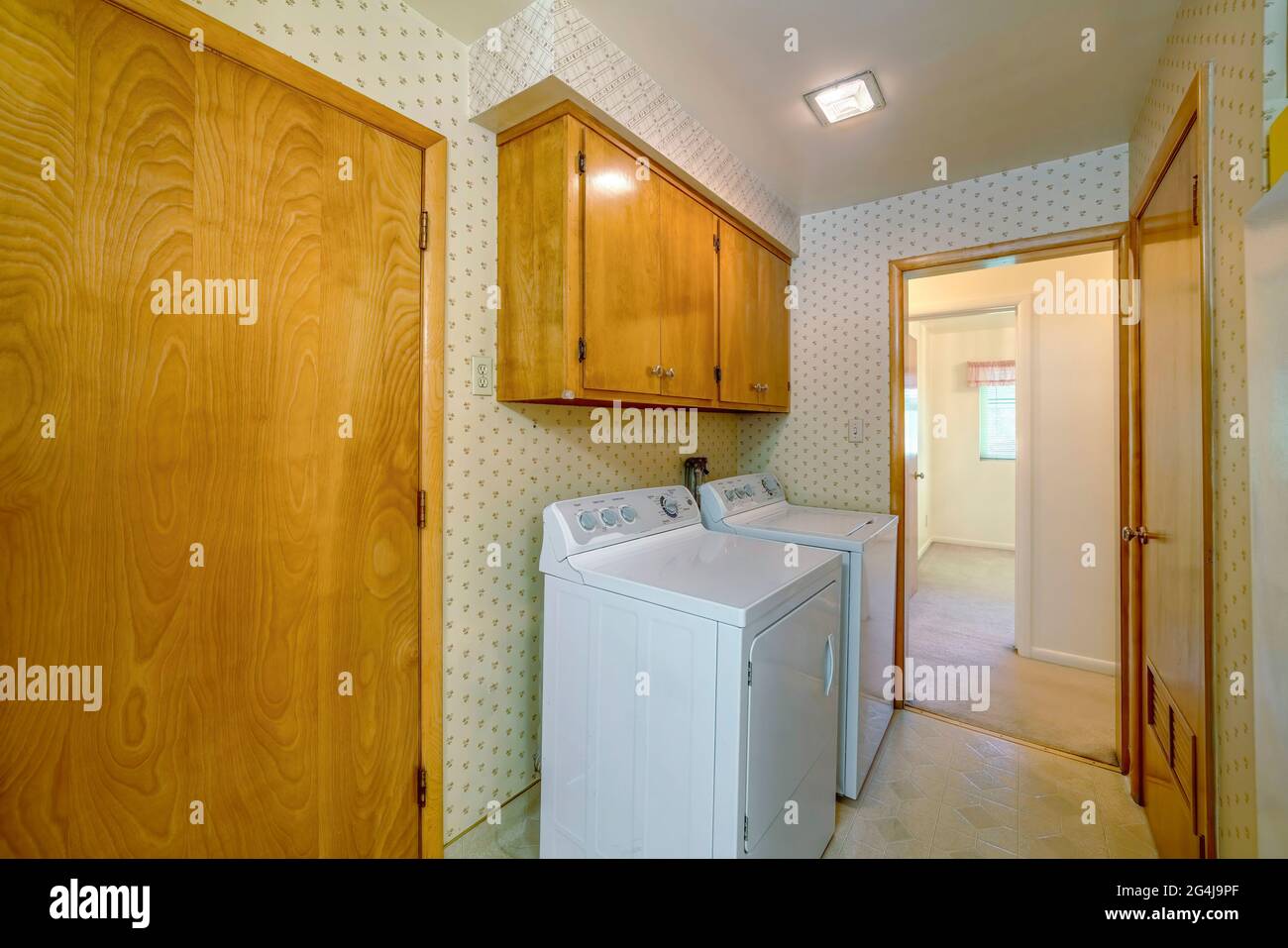 Laundry room with a washing machine, a dryer, and wooden cabinets for ...