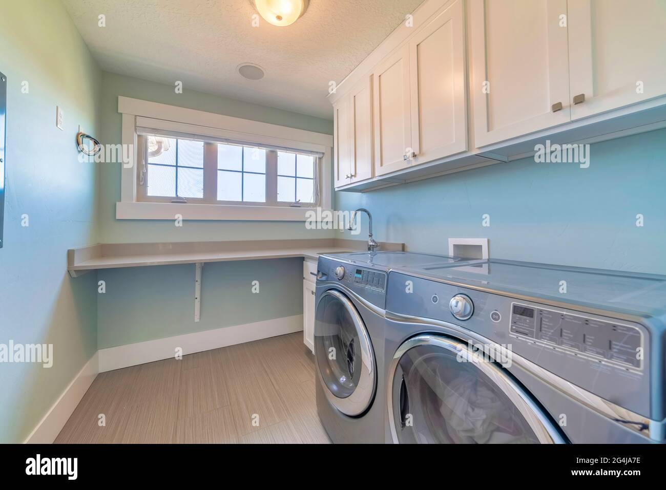 Laundry room with a washing machine, a dryer, and wooden cabinets for ...