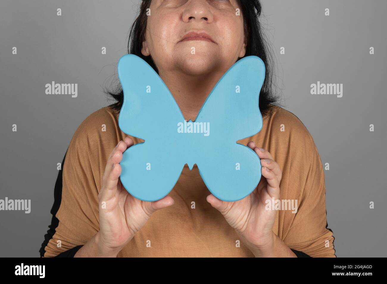 woman holding a butterfly shape in front of her thyroid Stock Photo - Alamy