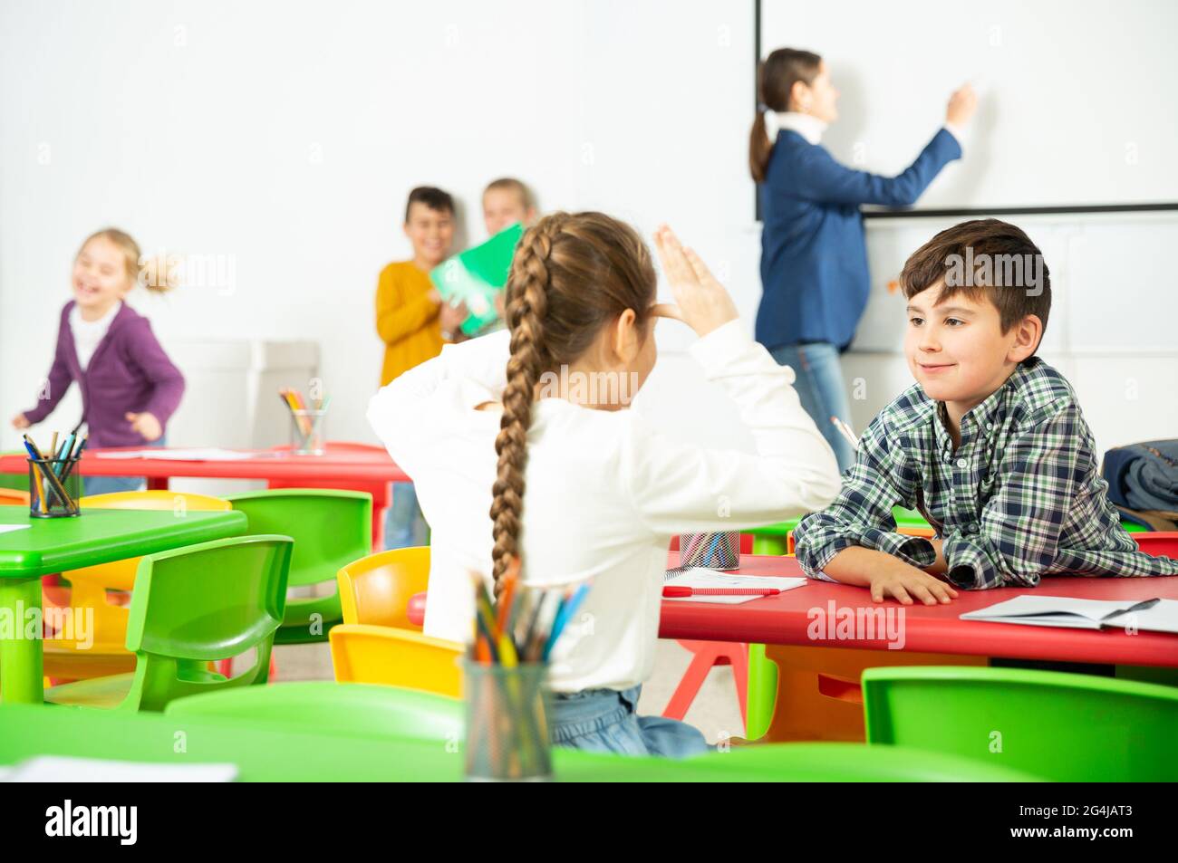 Portrait of schoolchildren sitting in classroom and chatting during ...