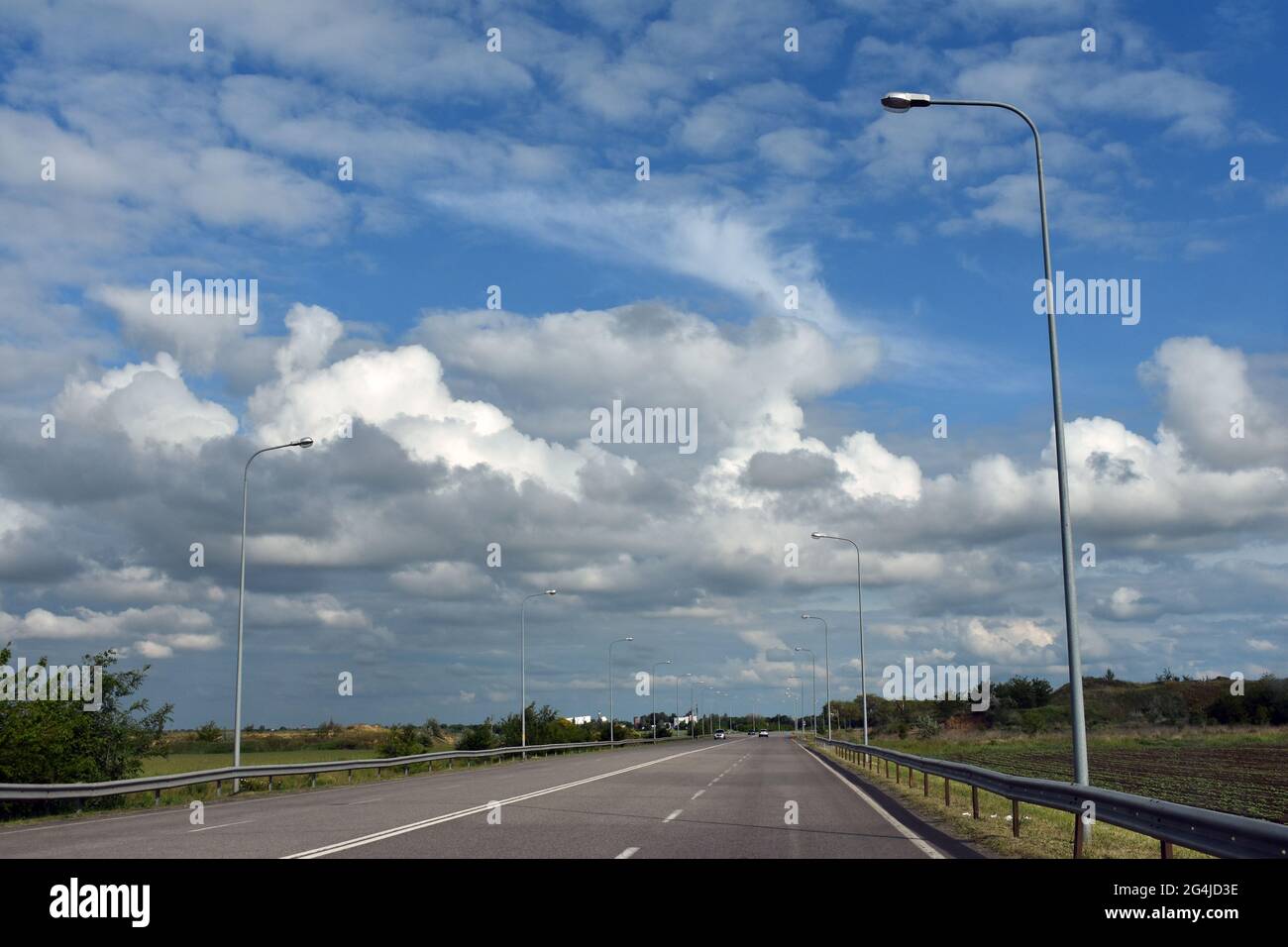 Empty street surrounded by vegetation with a cloudy sky over it Stock ...