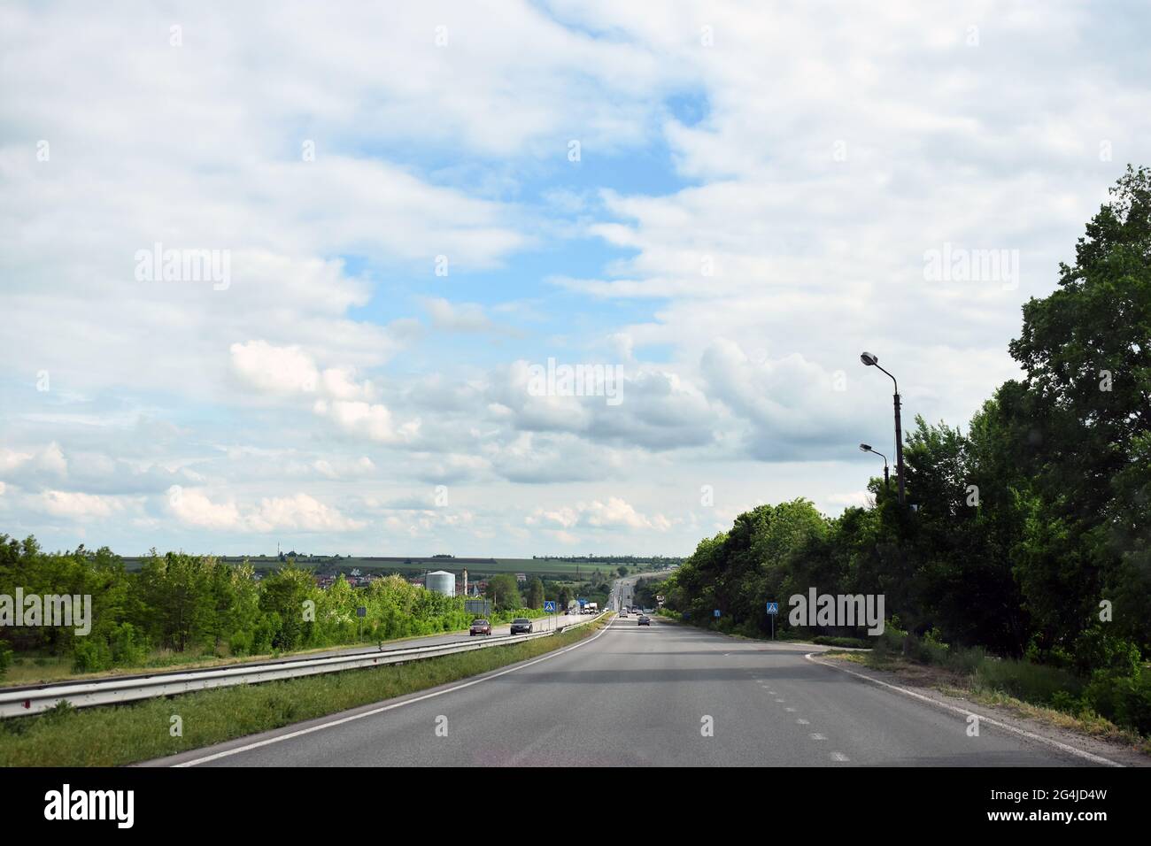 Empty street surrounded by vegetation with a cloudy sky over it Stock ...