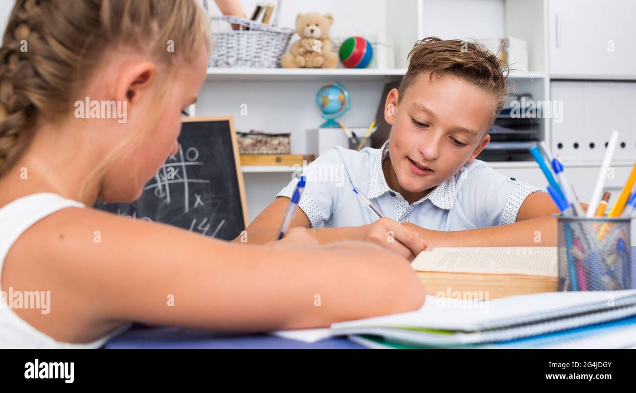 Boy with girl are writing in notebook their homework Stock Photo - Alamy