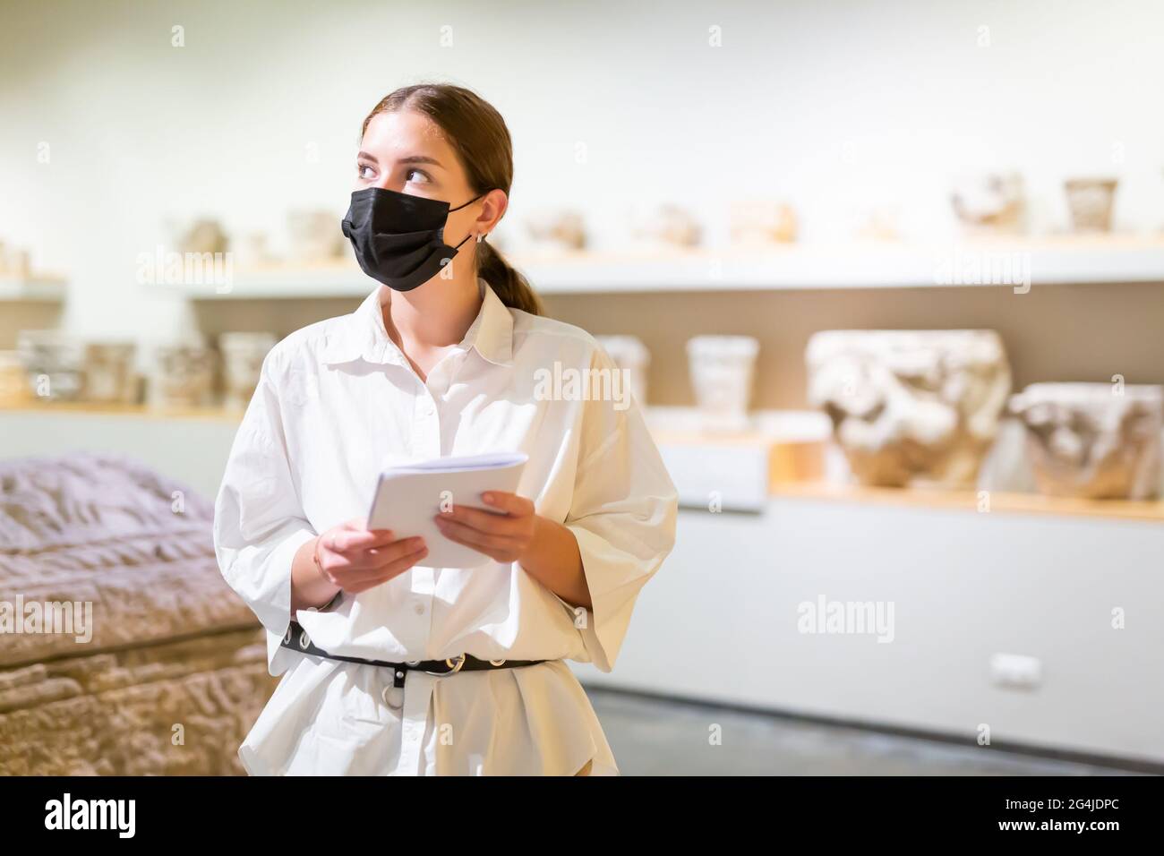 Woman in mask visiting exhibit at sculpture hall in museum Stock Photo ...