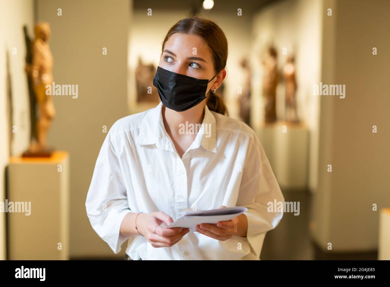 Woman in mask visiting exhibit at sculpture hall in museum Stock Photo ...