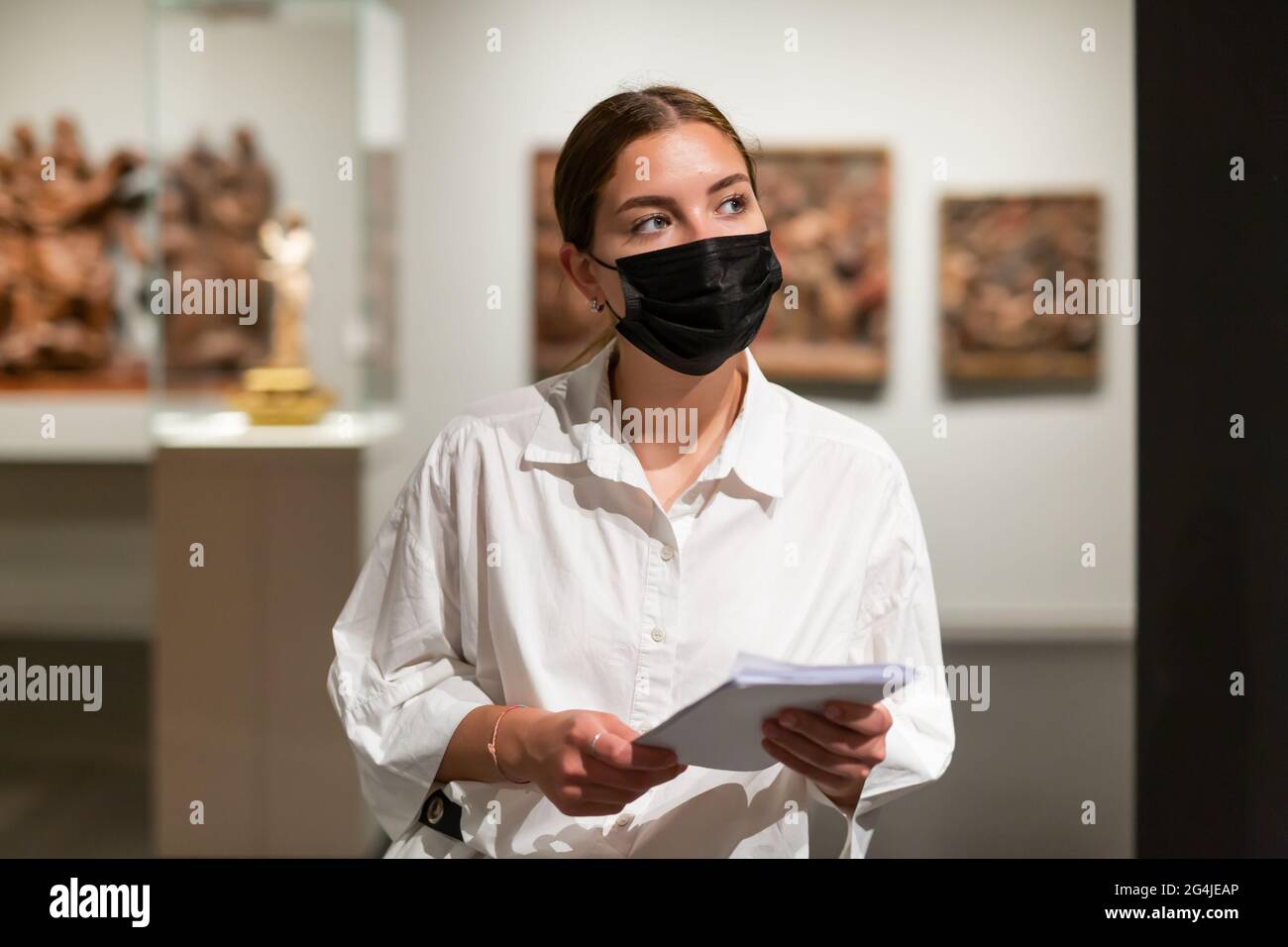 Woman in mask visiting exhibit at sculpture hall in museum Stock Photo ...