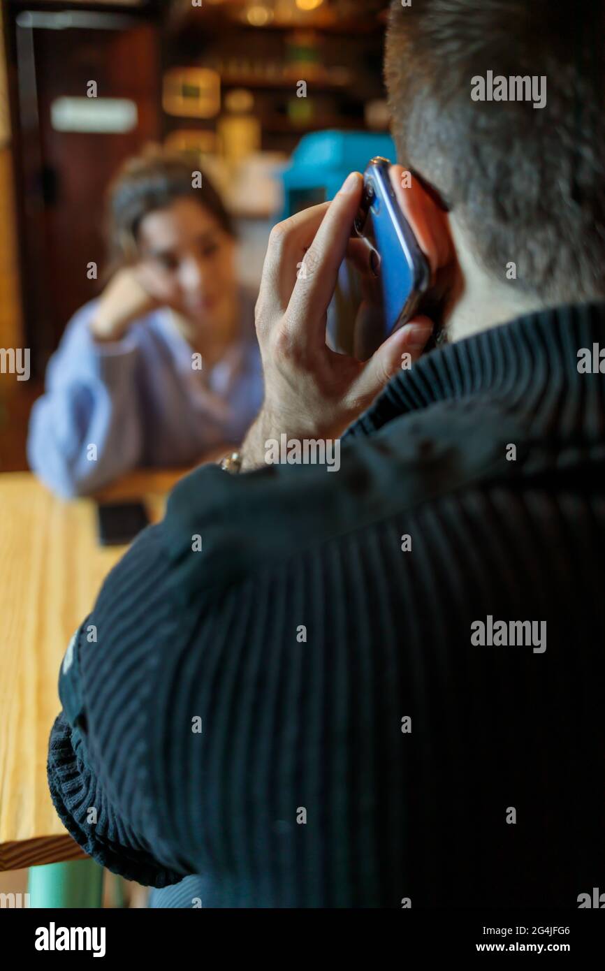 Vertical shot of a guy talking on the phone while the lady in front of ...