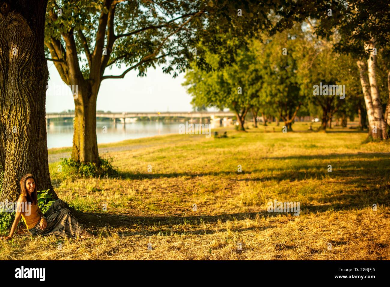 Caucasian female posing sitting under a tree Stock Photo - Alamy