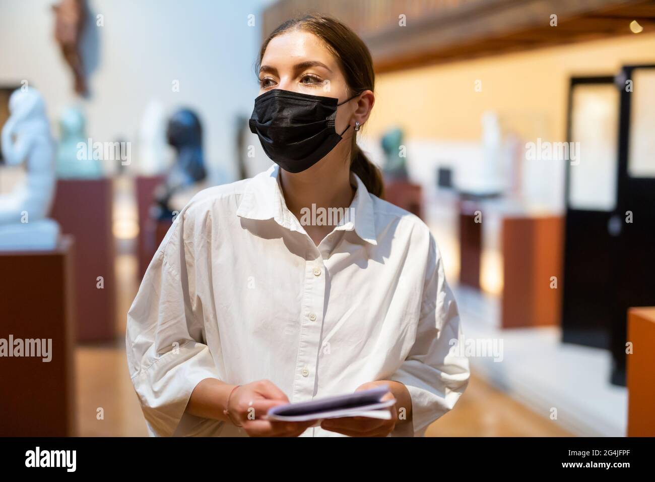 Woman in mask visiting exhibit at sculpture hall in museum Stock Photo ...