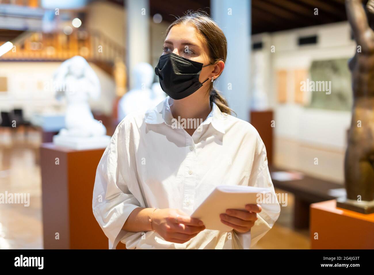 Woman in mask visiting exhibit at sculpture hall in museum Stock Photo ...