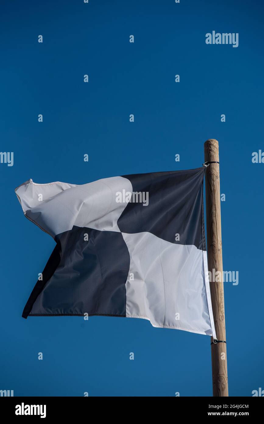 Checkered black and white flag on the beach of Es Arenal on the island ...