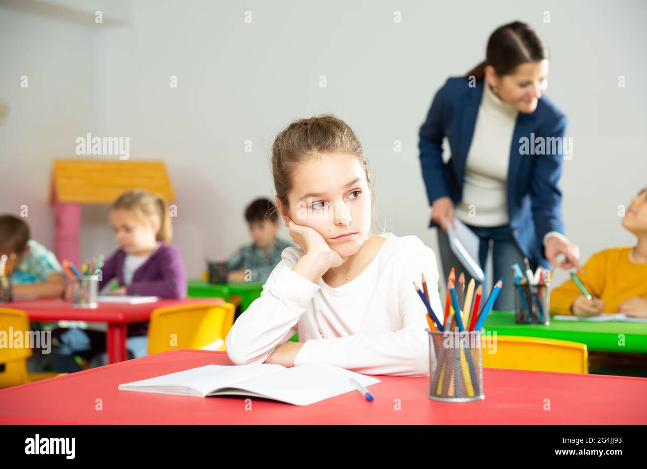 Portrait of tired schoolgirl sitting in classroom elementary school ...