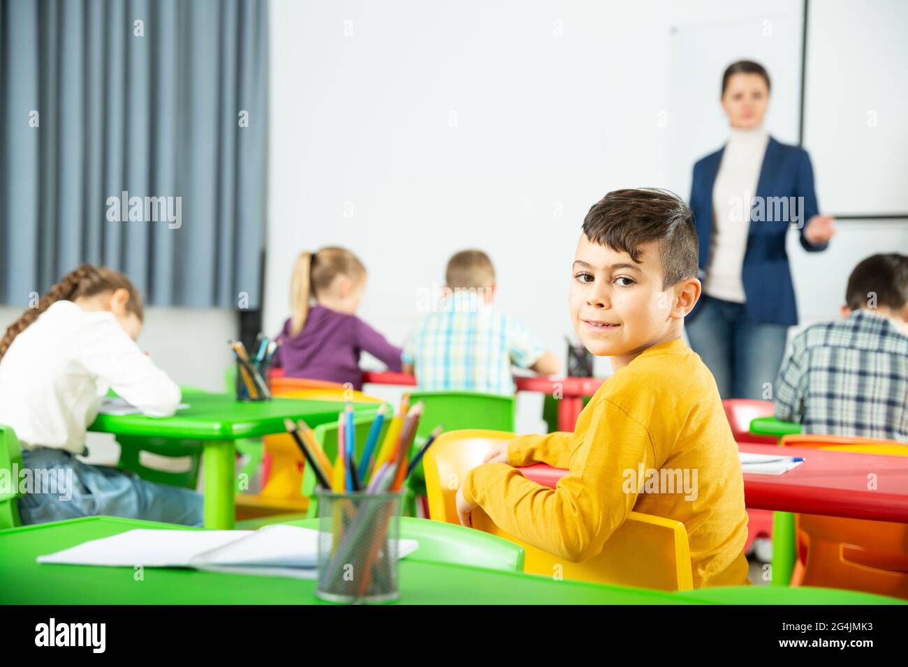 Portrait of little assiduous boy with pen and notebook at lesson in ...