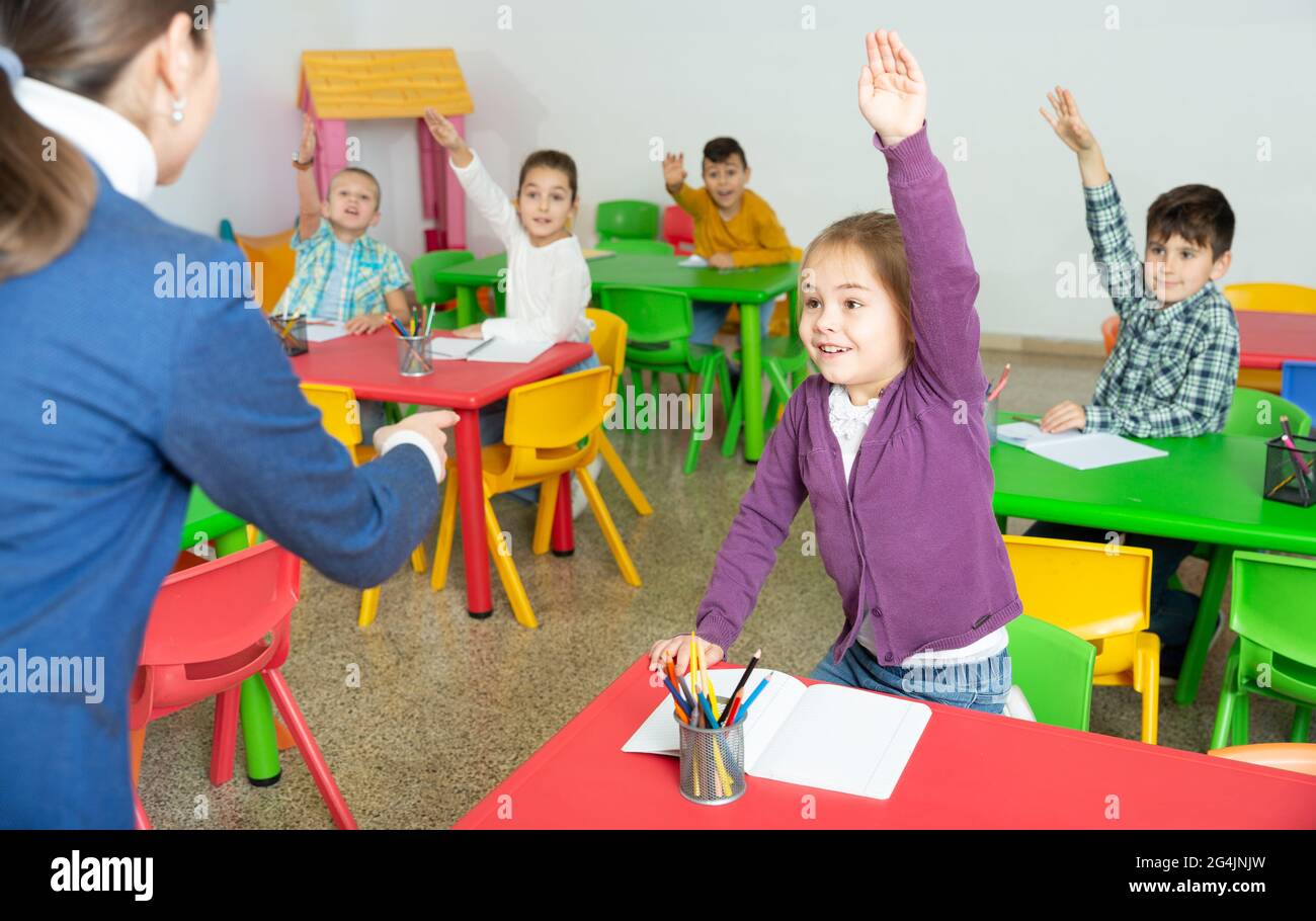 Happy schoolchildren with hands raised during lesson Stock Photo - Alamy Happy schoolchildren with hands raised during lesson Stock Photo - Alamy