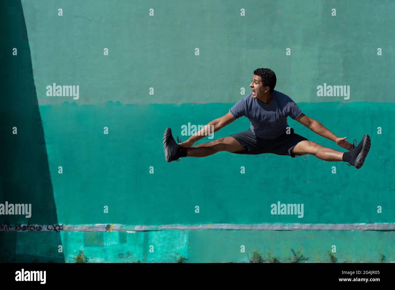 Energetic Mexican guy jumping with arms and legs outstretched Stock ...