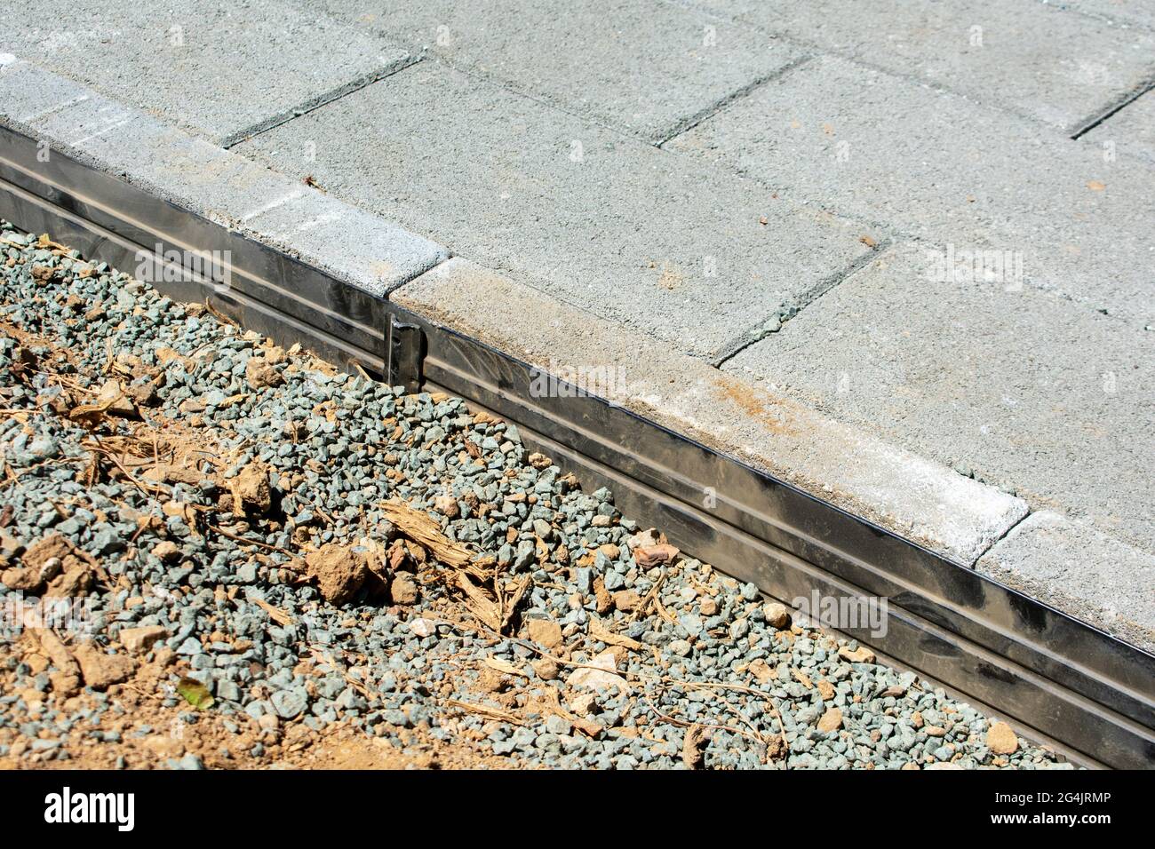 Gray stone pavers installation in progress. Metal edge restraint system ...