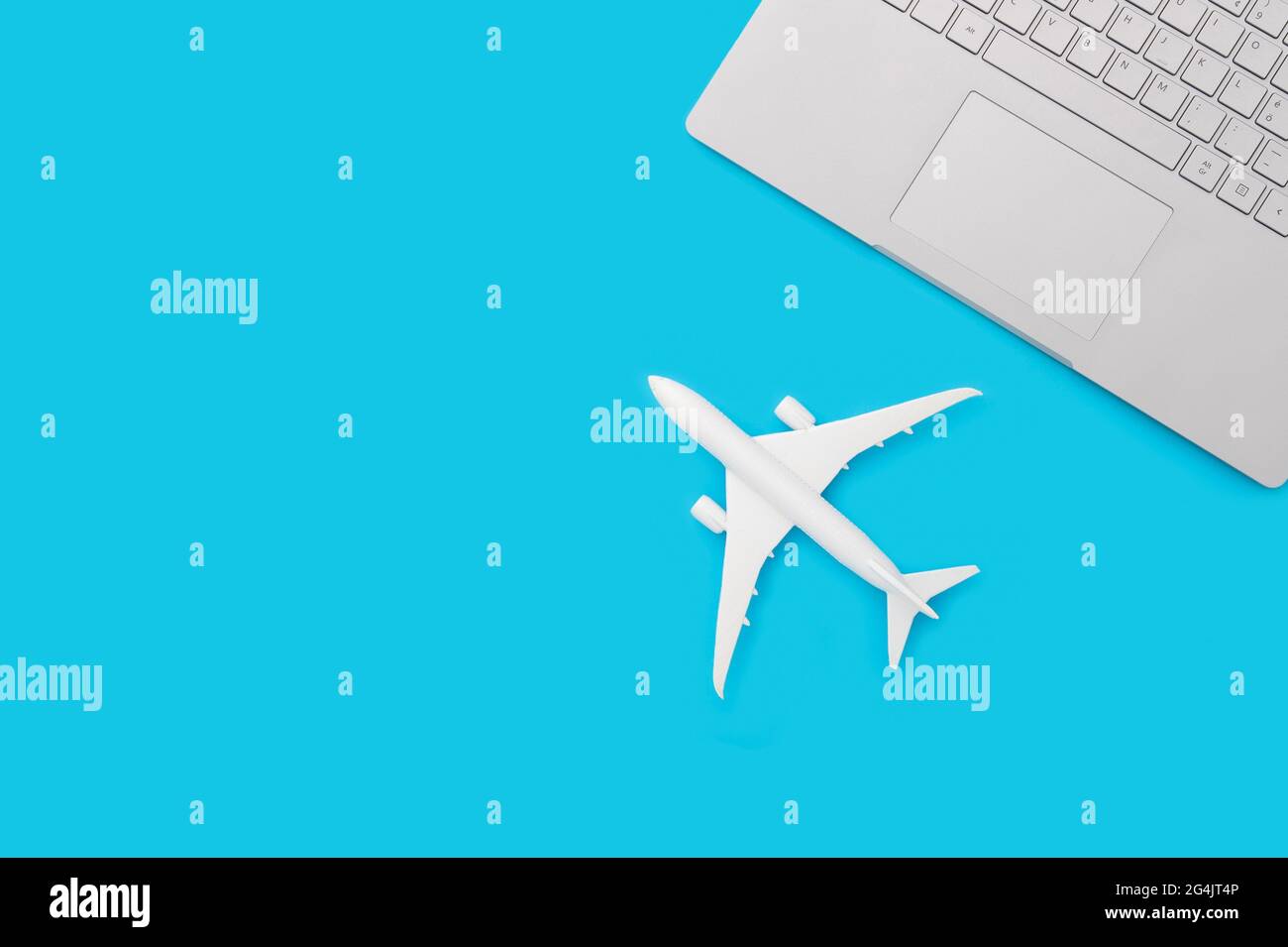 Small, white plane in front of a gray notebook with a blue background ...