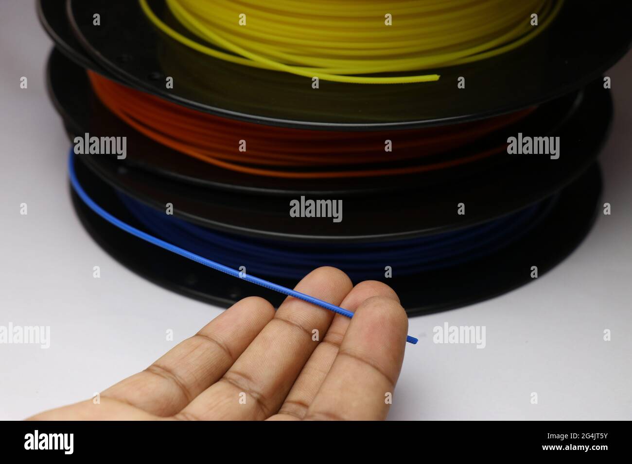 Multicolor filament spools or reels laid flat with hands holding blue ...