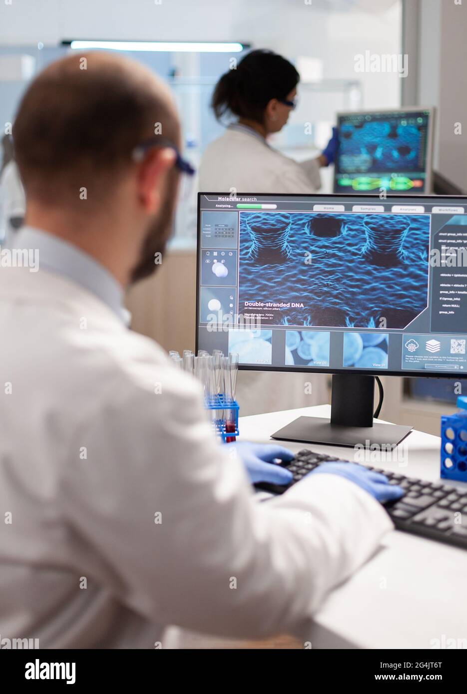 Man biologist checking DNA informations typing on pc in modern equipped ...