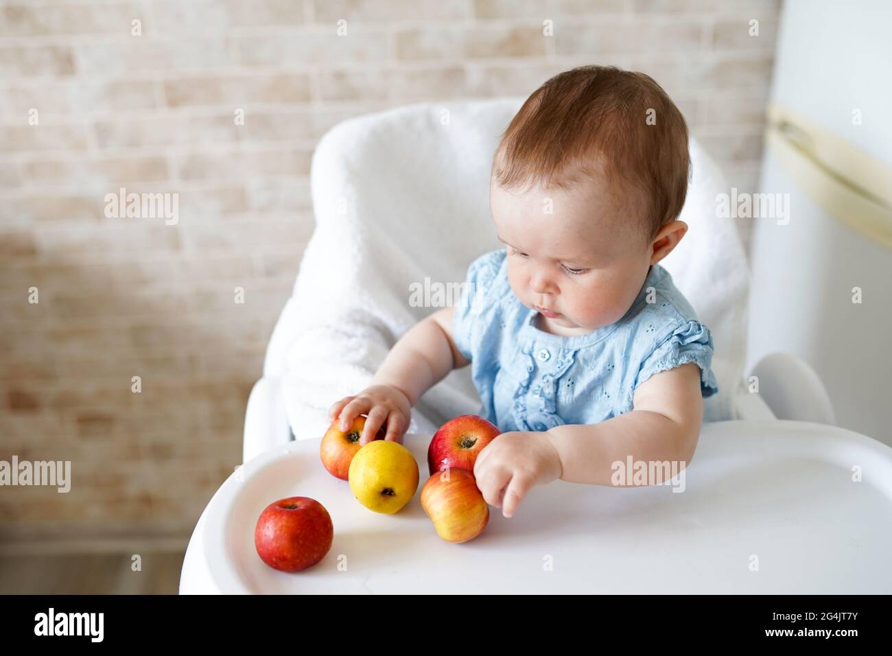 Baby eating fruit. Little girl biting yellow apple sitting in white ...