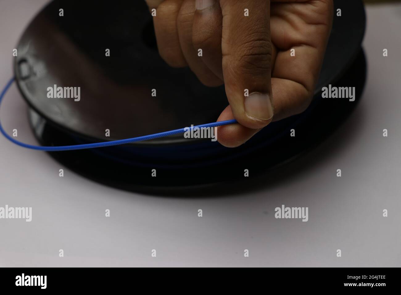 Blue color filament material held in hand from a spool. 3D Printer use ...