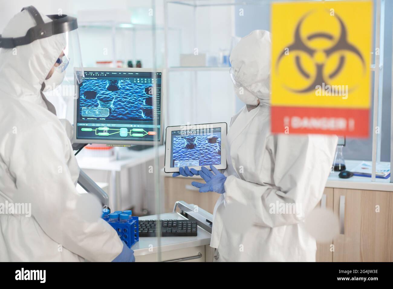 Doctors wearing ppe suit working in lab danger zone area using tablet ...