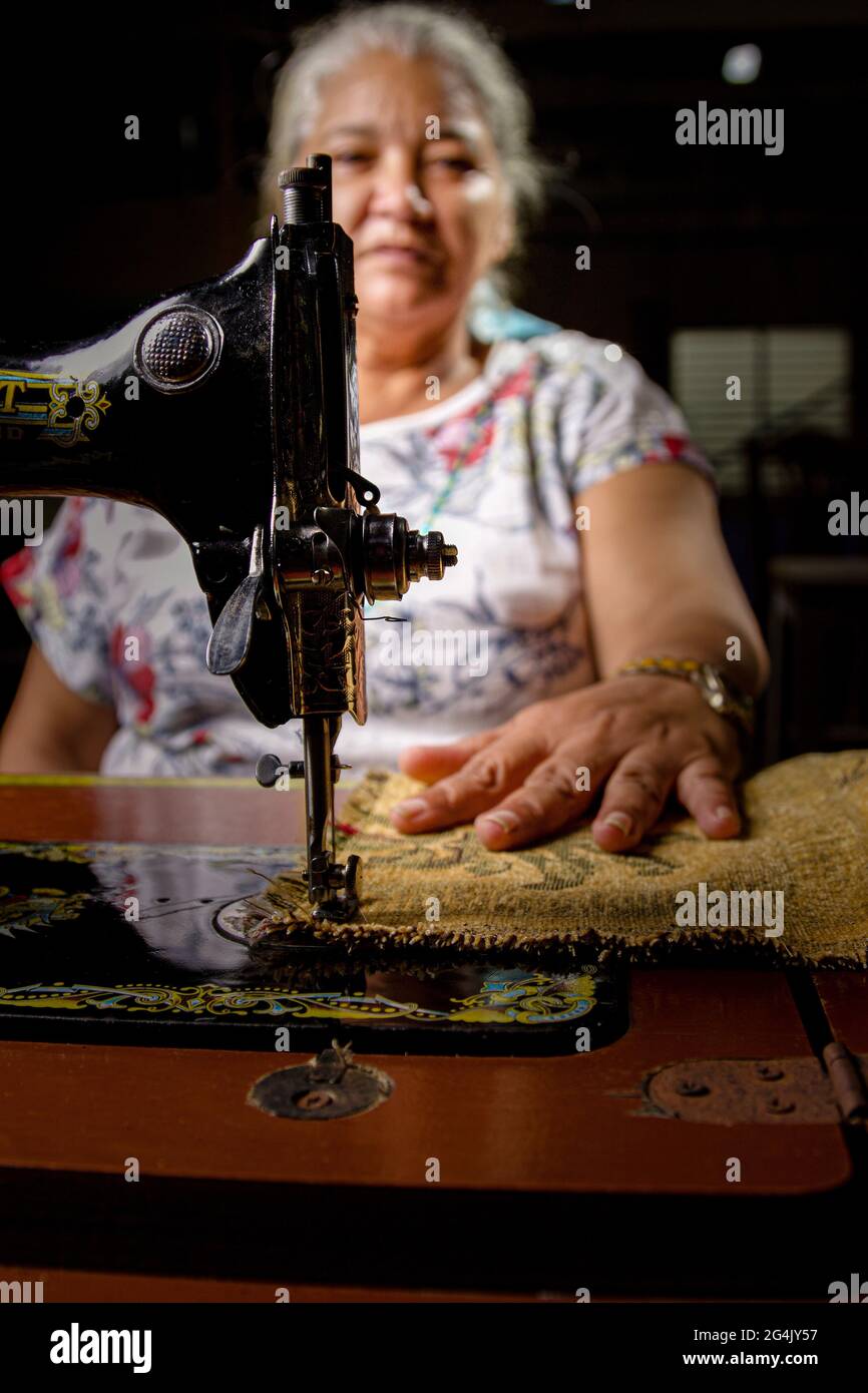 Vertical shot of a senior Caucasian female sewing with a vintage sewing ...