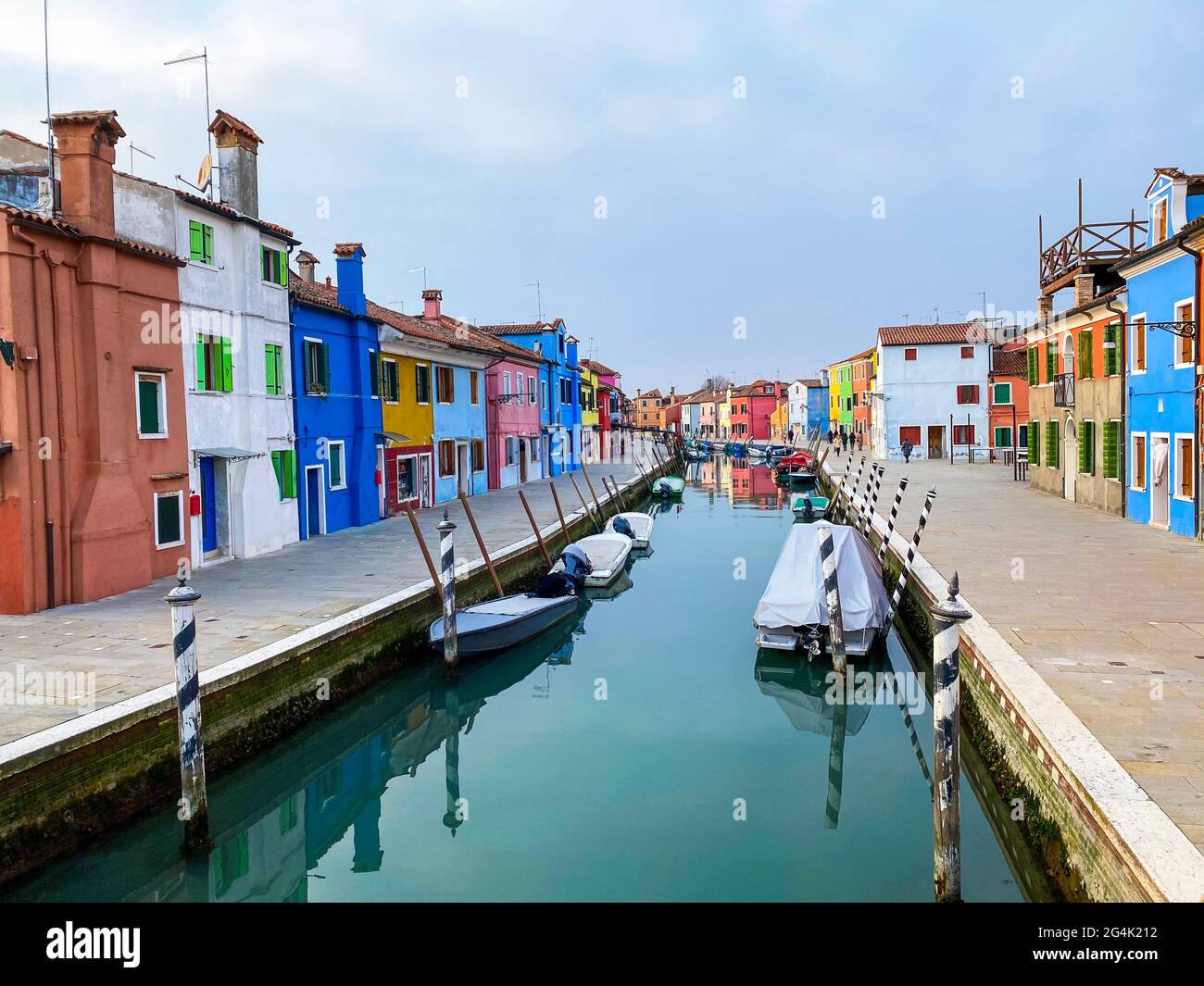 Boats docking and colorful houses in a canal street houses on Burano ...