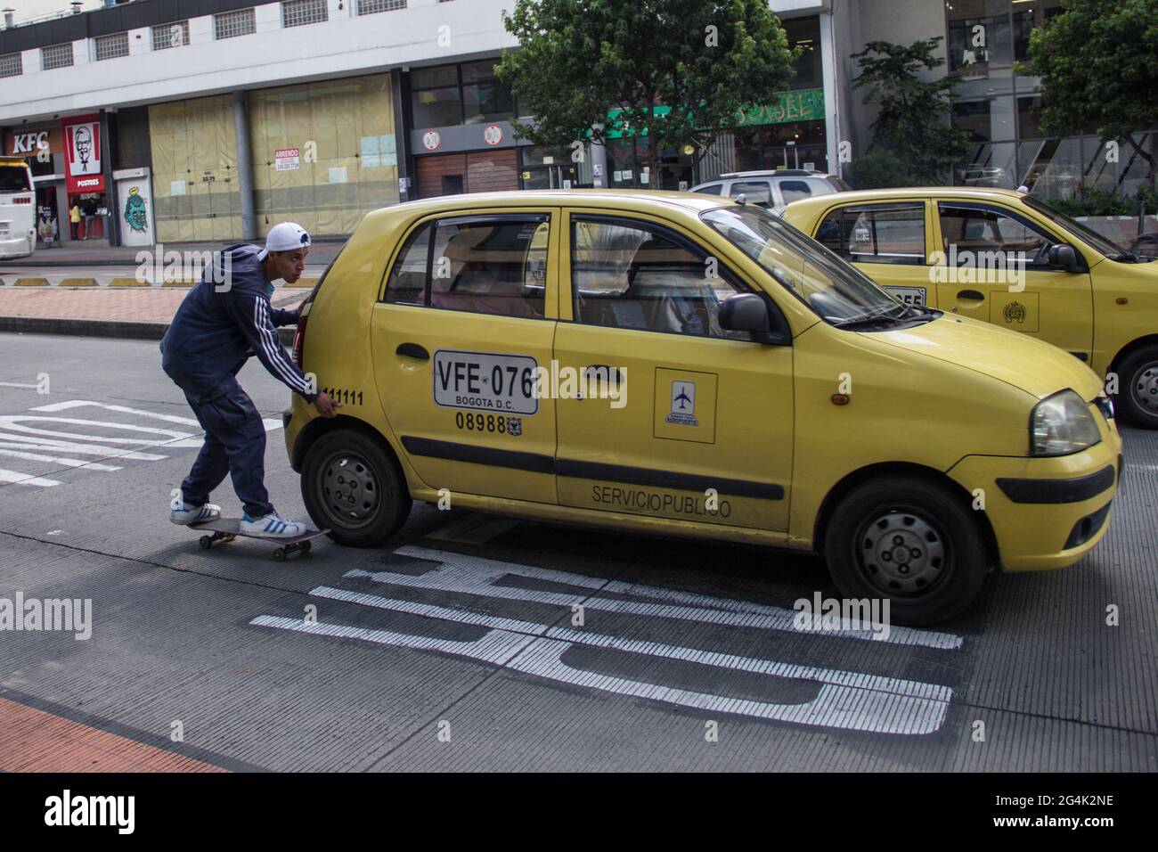 A skater rides attached to the back of a cab as the passanger watches ...