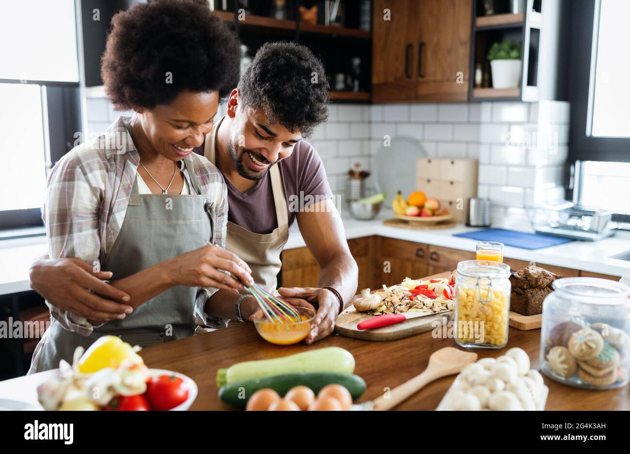 Beautiful young couple having fun and laughing while cooking in kitchen ...