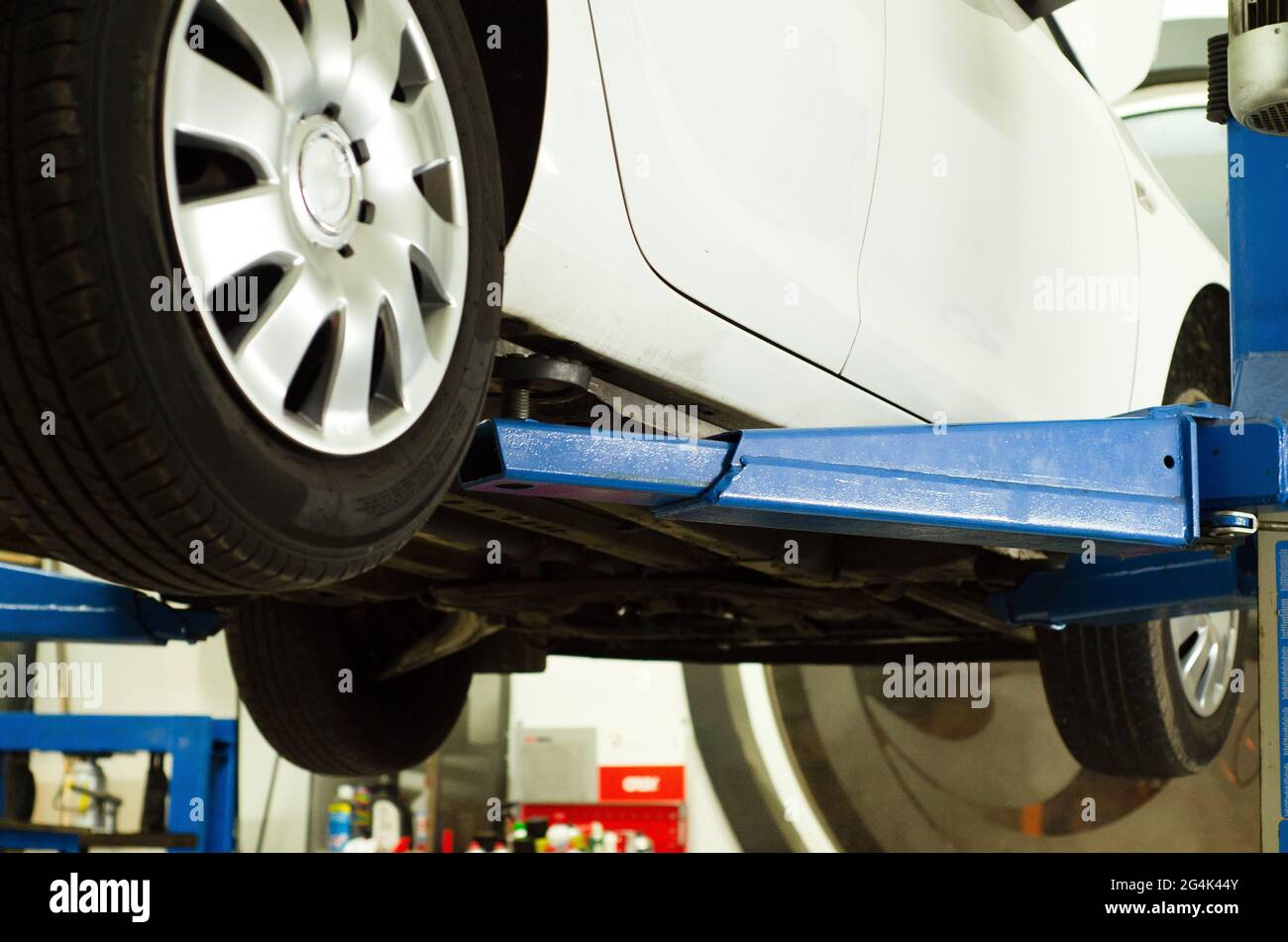 Low angle shot of a white lifted car on a hydraulic ramp Stock Photo ...