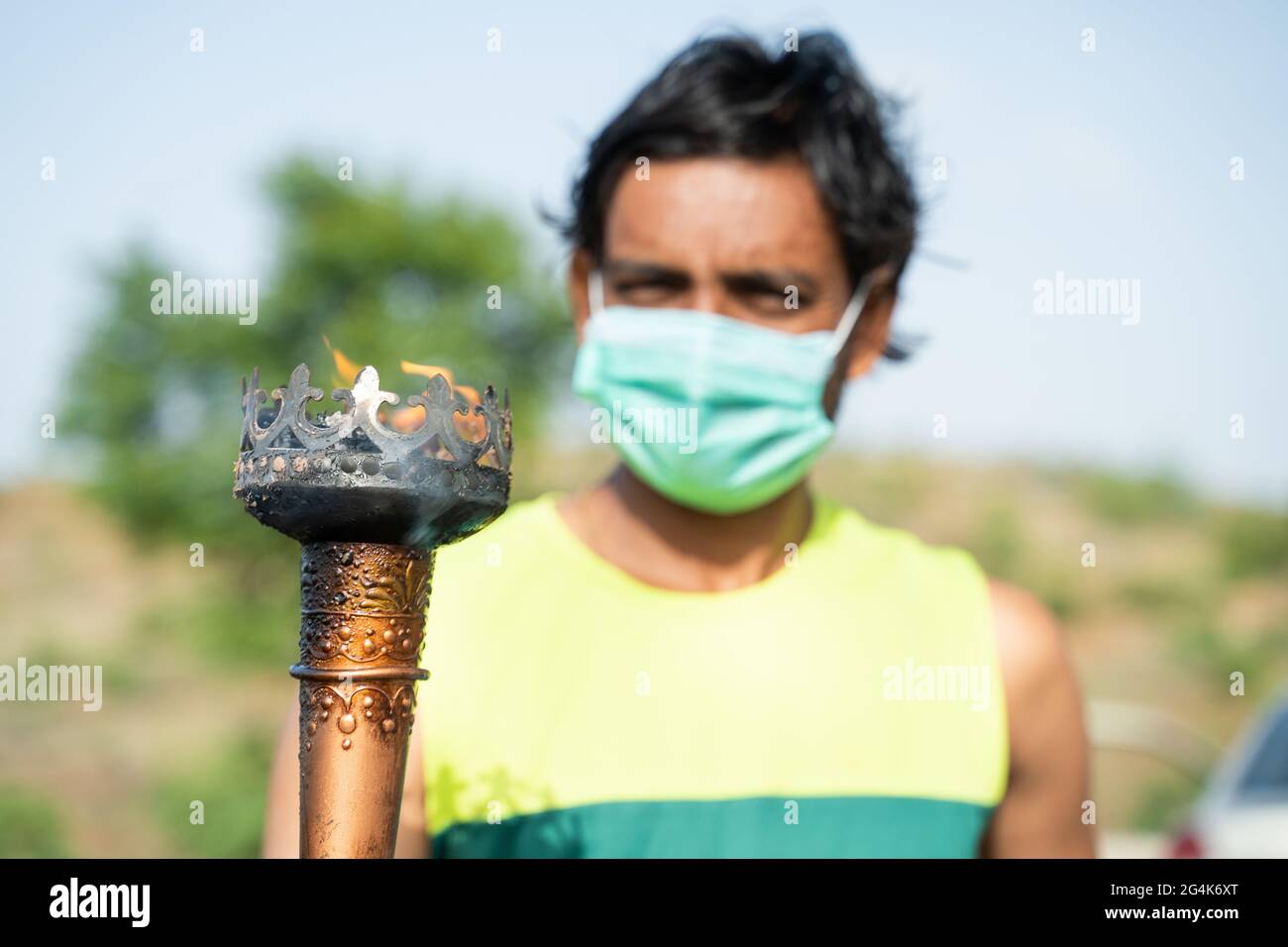 young athlete with medical face mask seeing Olympic flame torch ...