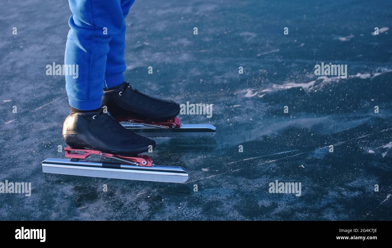 The child train on ice speed skating. The legs in skates close up. The ...